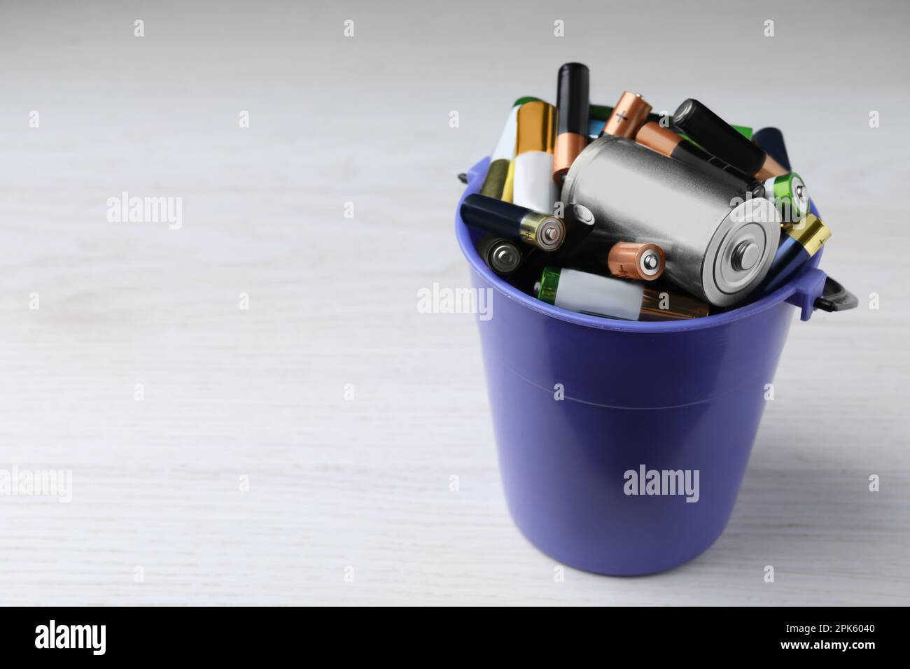 Used batteries in bucket on white table, space for text Stock Photo - Alamy