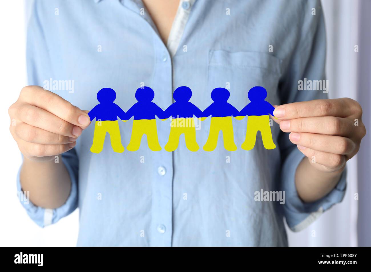 Woman holding paper people chain in colors of Ukrainian flag on light ...