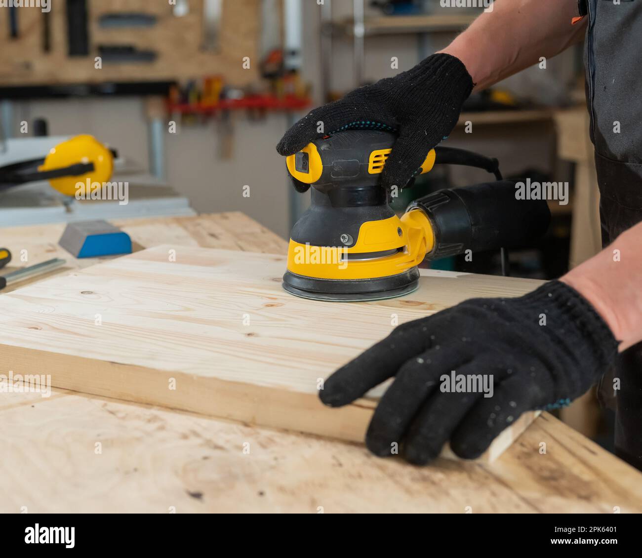 A man using an orbital wood sander in a workshop. Close-up of a ...