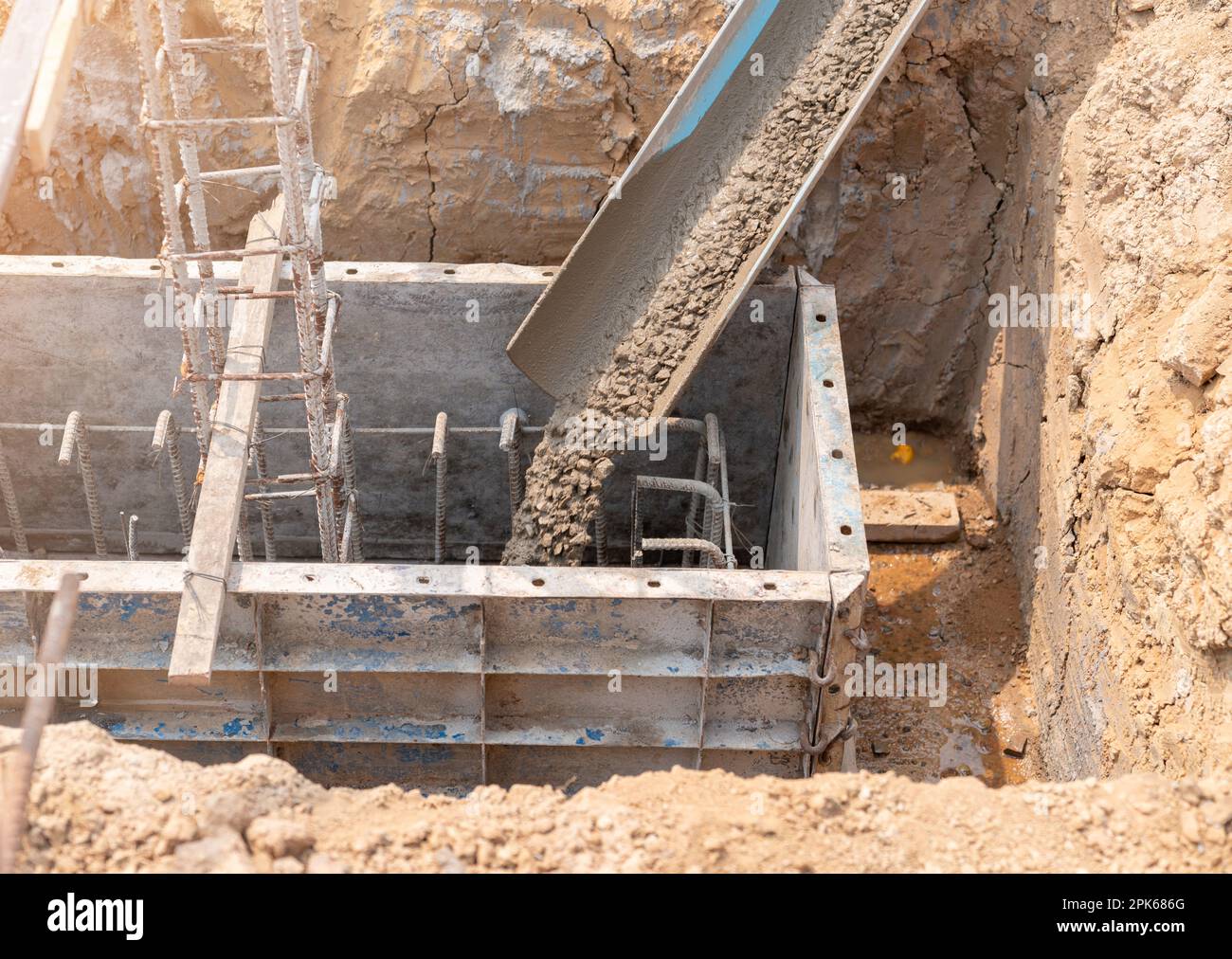 Pouring cement or concrete into foundation formwork of new building. Construction site details ...