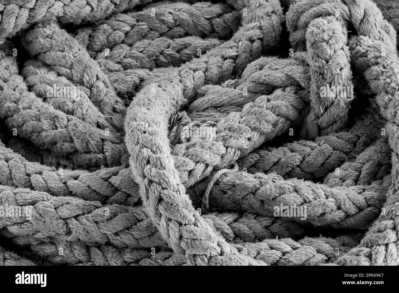 An old frayed rope lays in a heap on the deck of a ship, suggesting ...