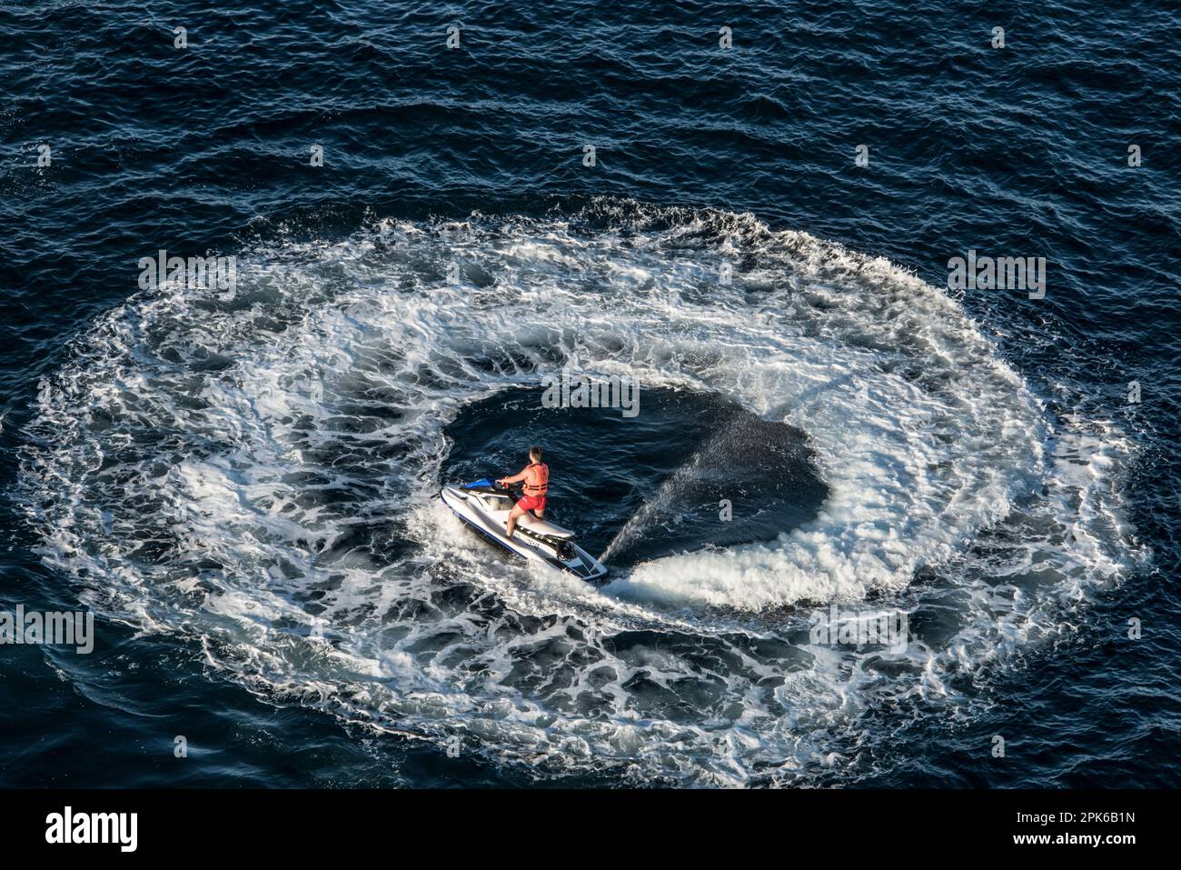A young man (unidentifiable) rides a jet ski personal watercraft ...