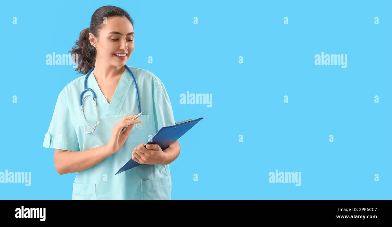 Female medical assistant with clipboard on light blue background with ...