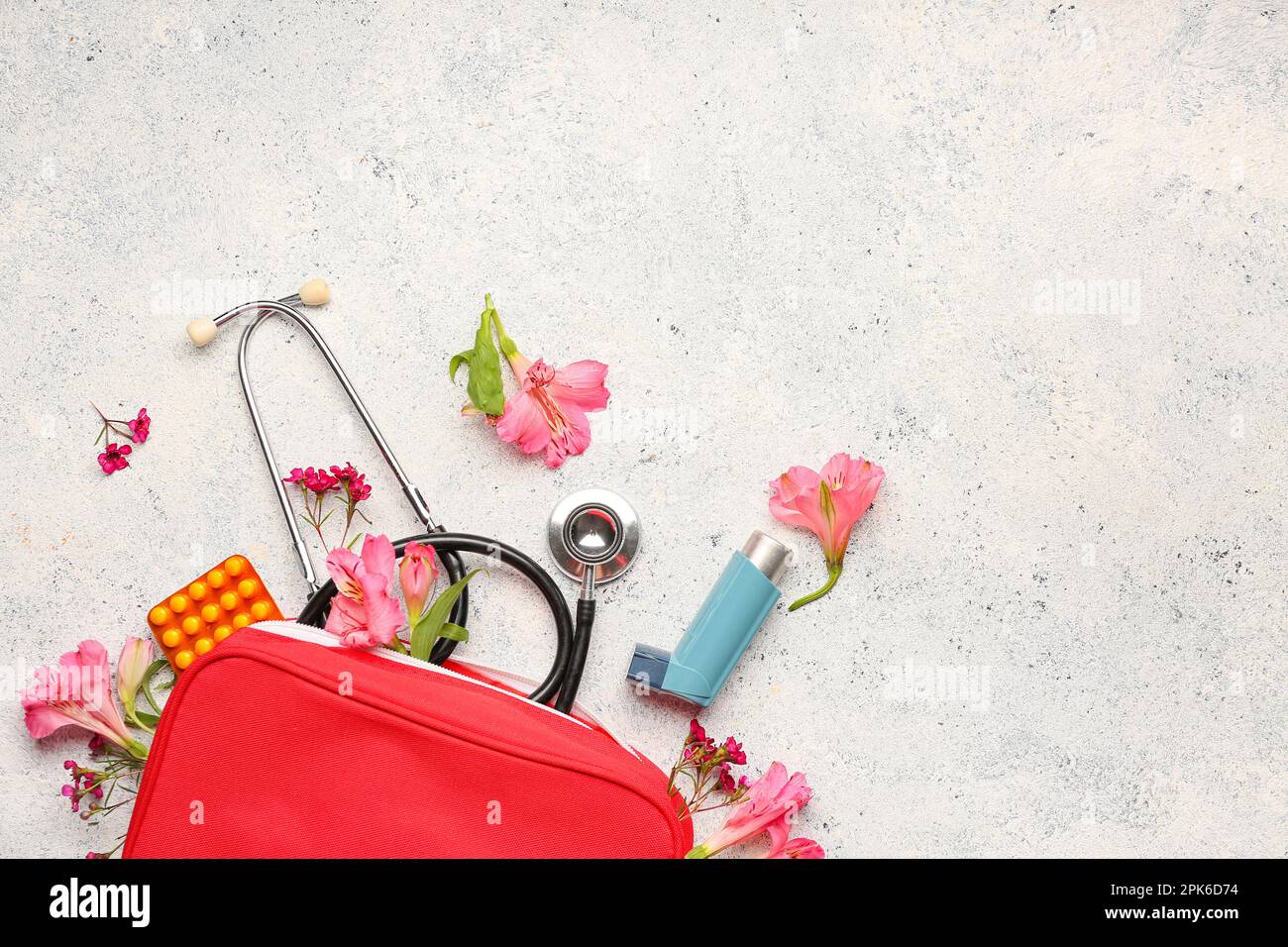 First aid kit with asthma inhaler, pills, stethoscope and flowers on ...
