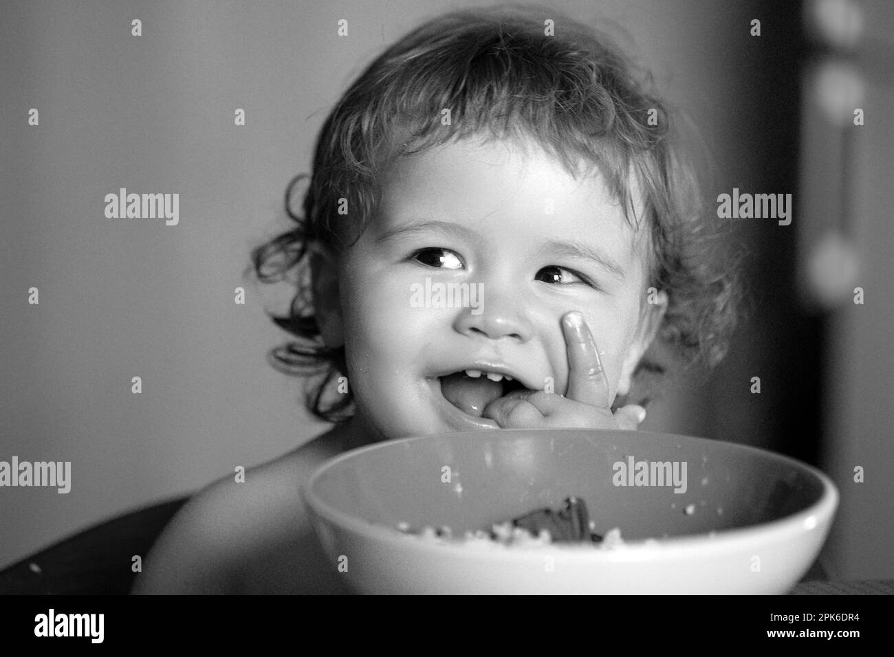 Healthy nutrition for kids. Funny baby eating food himself with a spoon ...