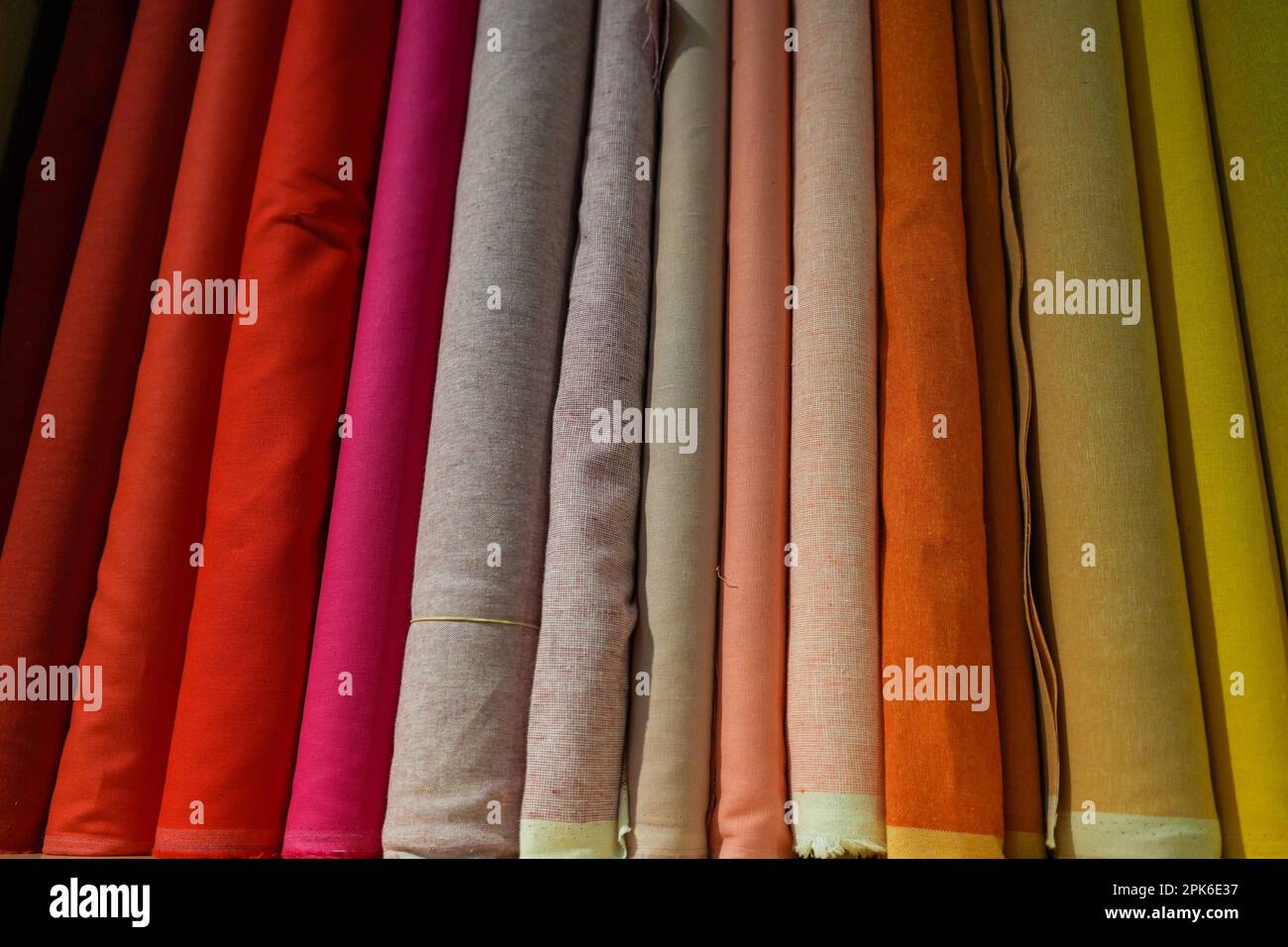 Rolls of colorful fabric on a wooden shelf in a store, solid colors ...
