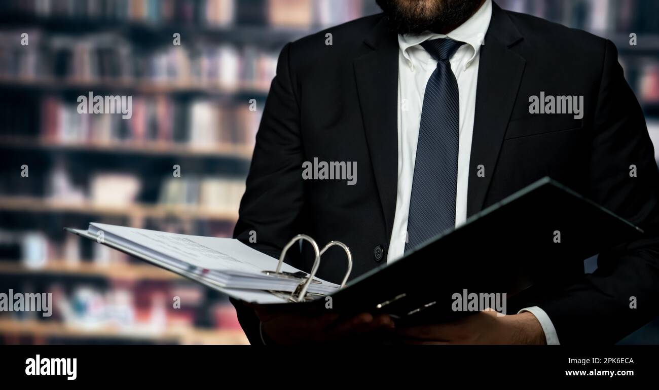 Sharp-suited businessman reviews and works on financial reports and ...