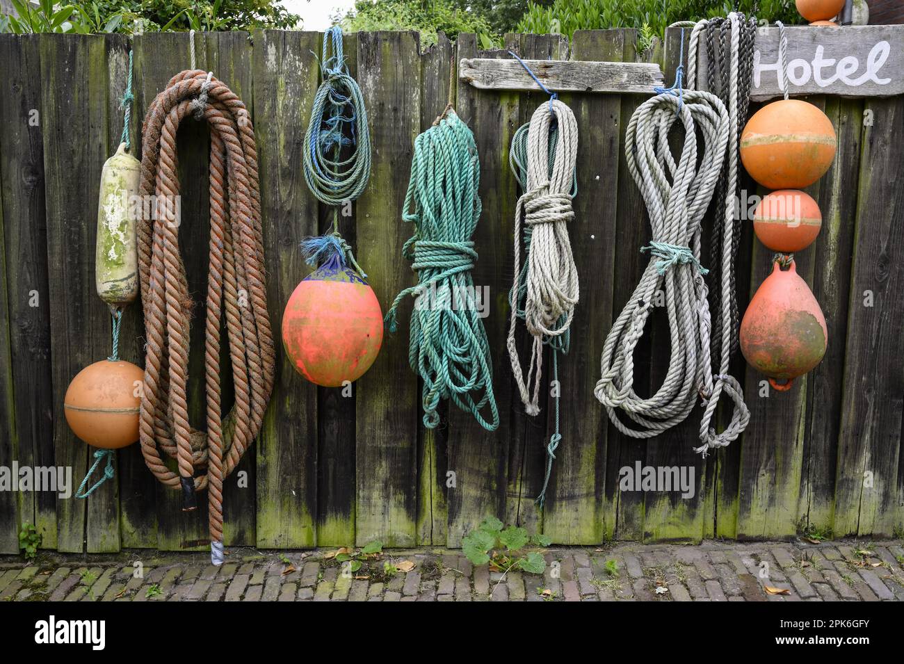 Old ropes and buoys on a fence, in the village of De Waal, Texel Island ...