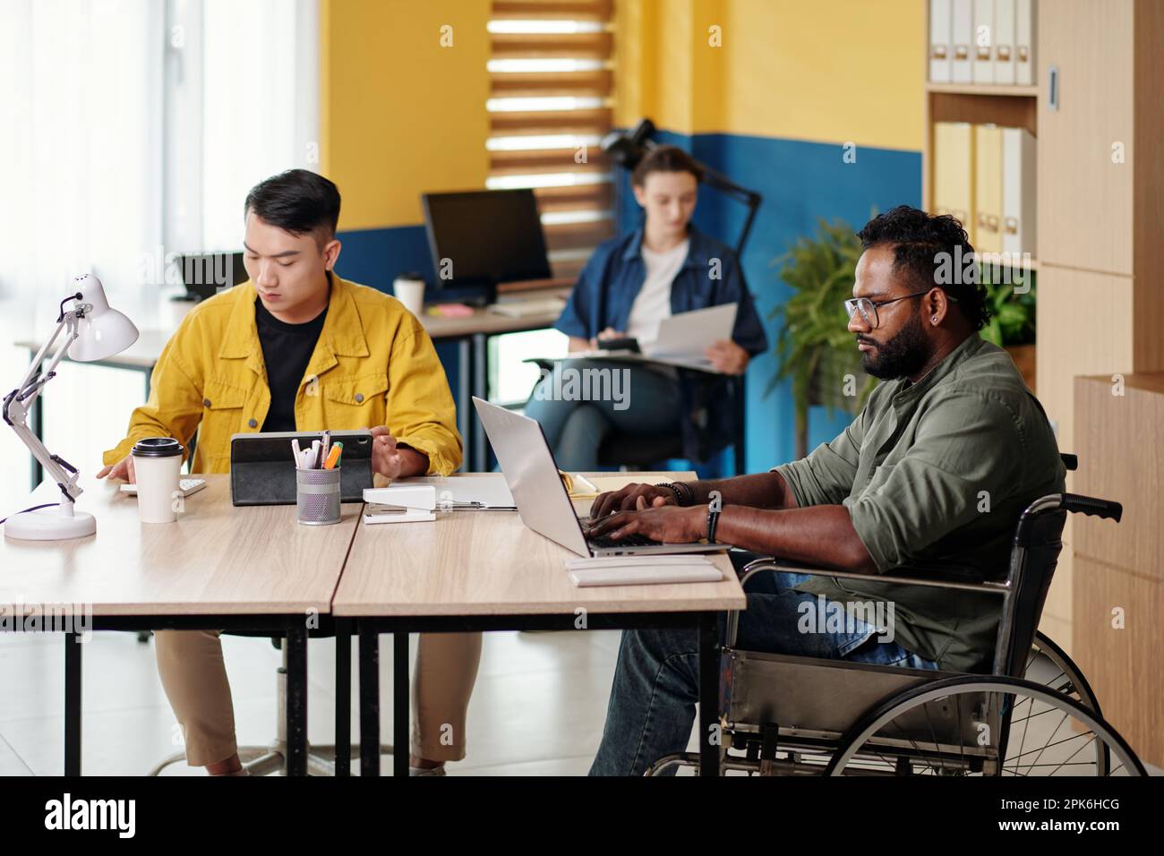 Man with disability working in office with diverse business team Stock ...