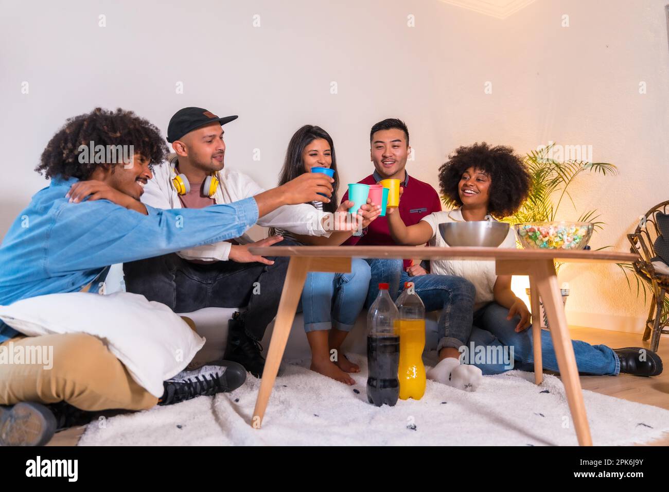 Group of friends eating popcorn and toasting with soft drinks. Laughing ...