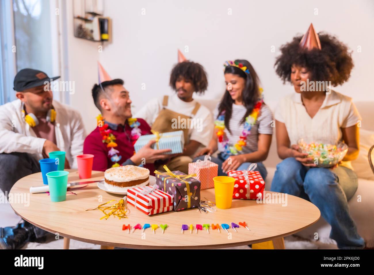 Group of friends at a birthday party on the sofa at home smiling ...