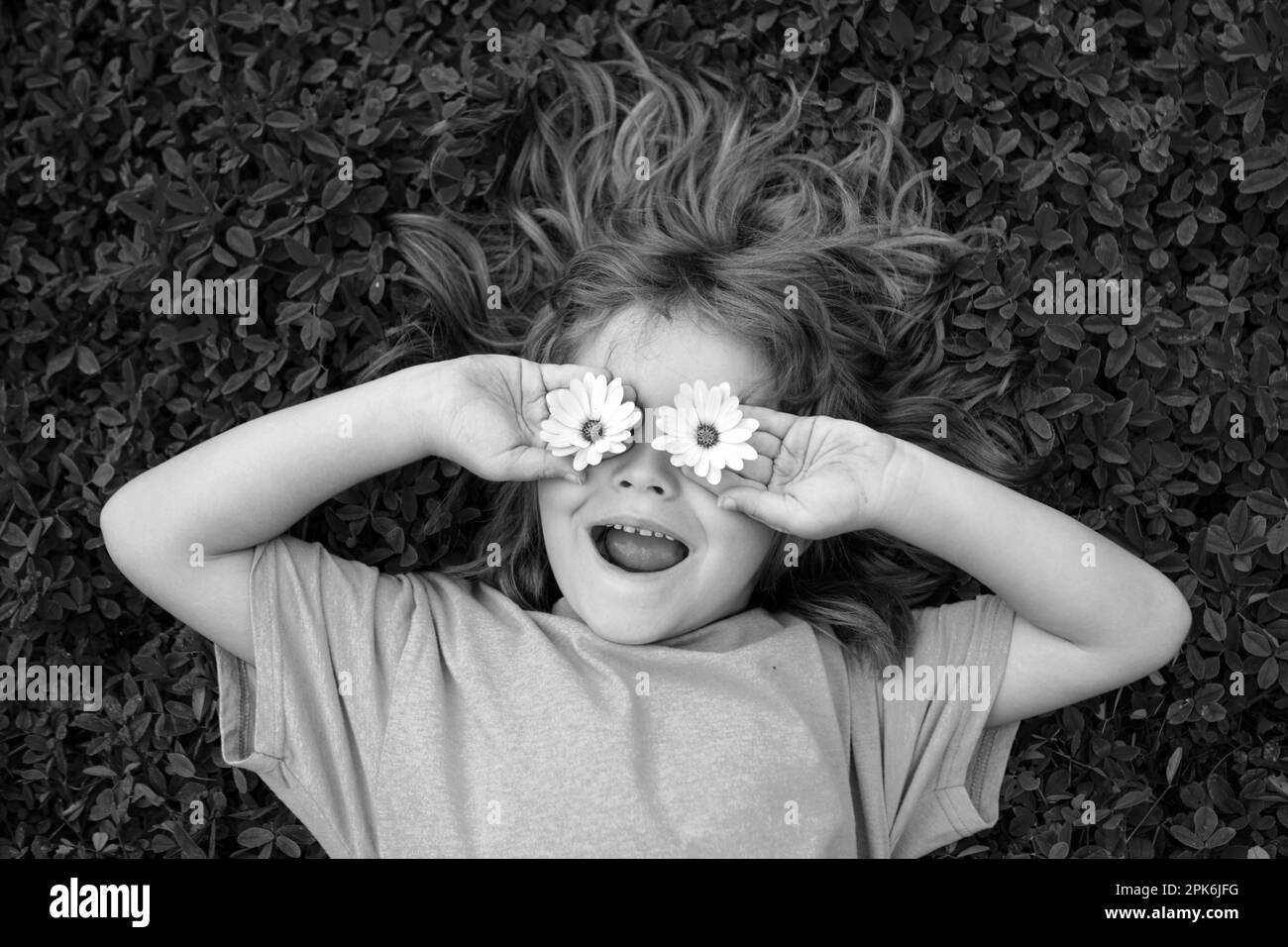 Top view spring child portrait. Funny kid smile and lay on grass ...