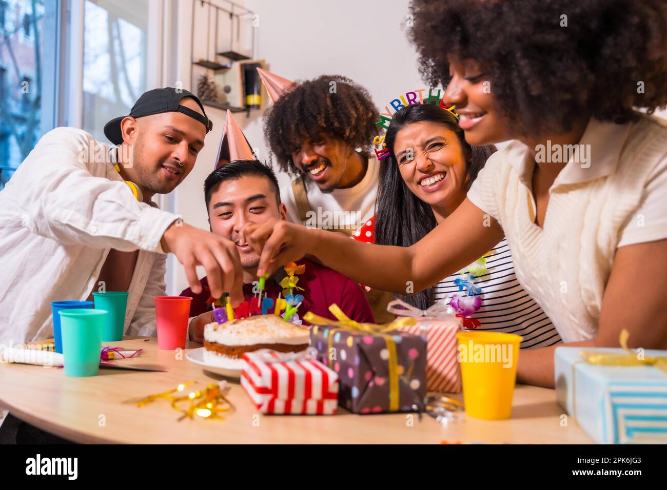 Multi-ethnic group of friends at a birthday party on the sofa at home ...