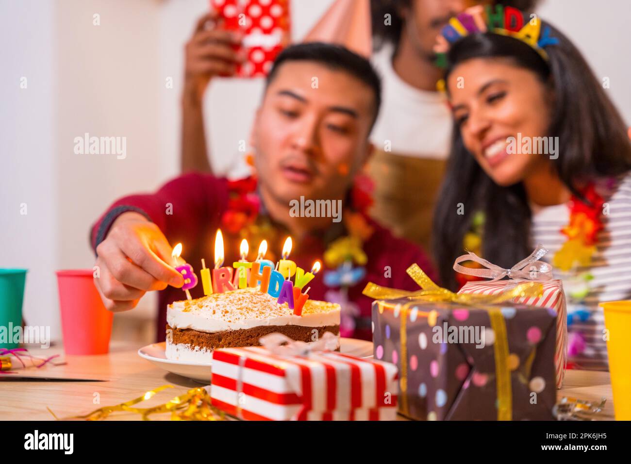 Multi-ethnic group of friends at a birthday party on the sofa at home ...