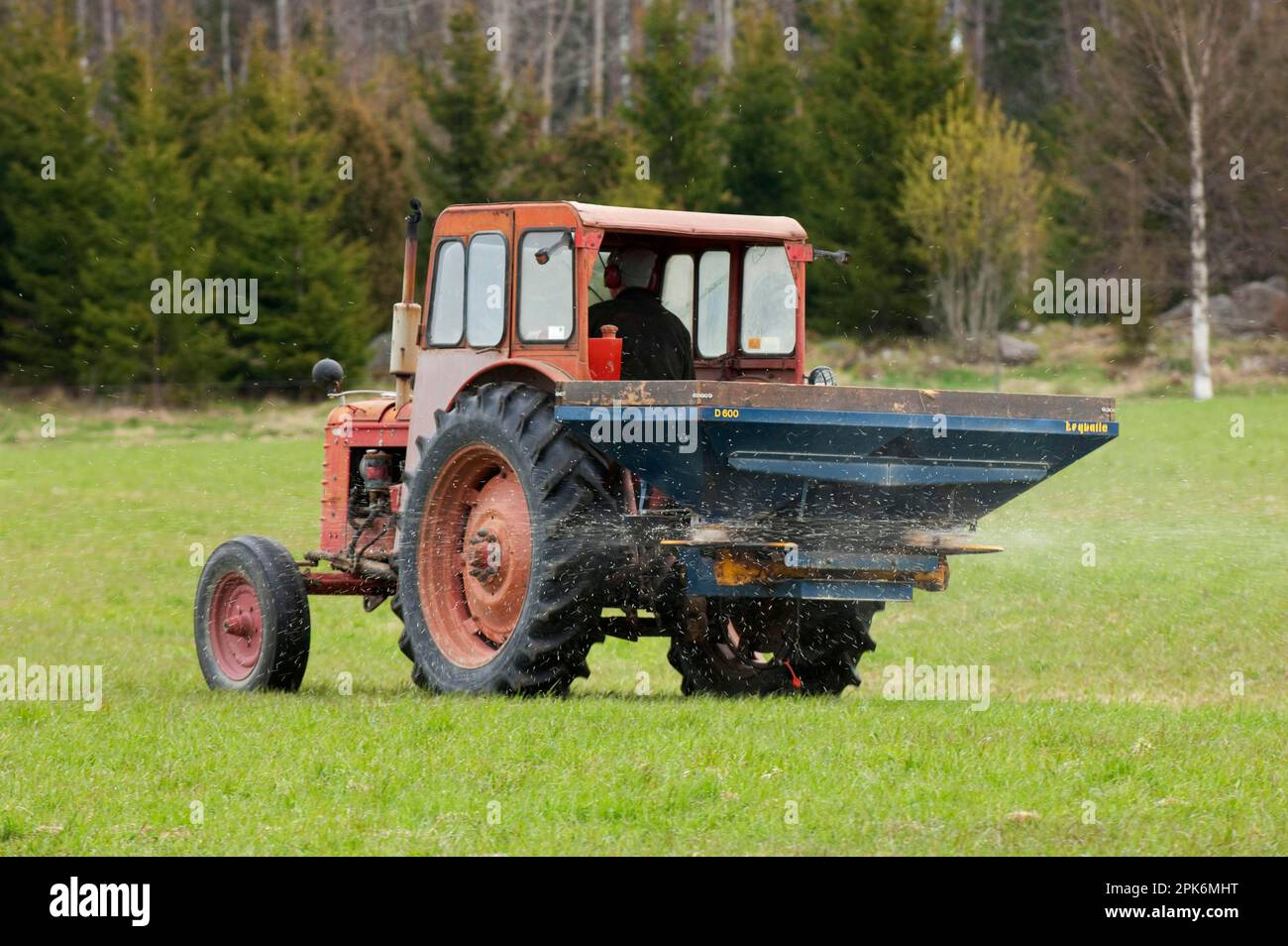 Tractor with fertiliser spreader applying nitrogen granulate fertiliser ...