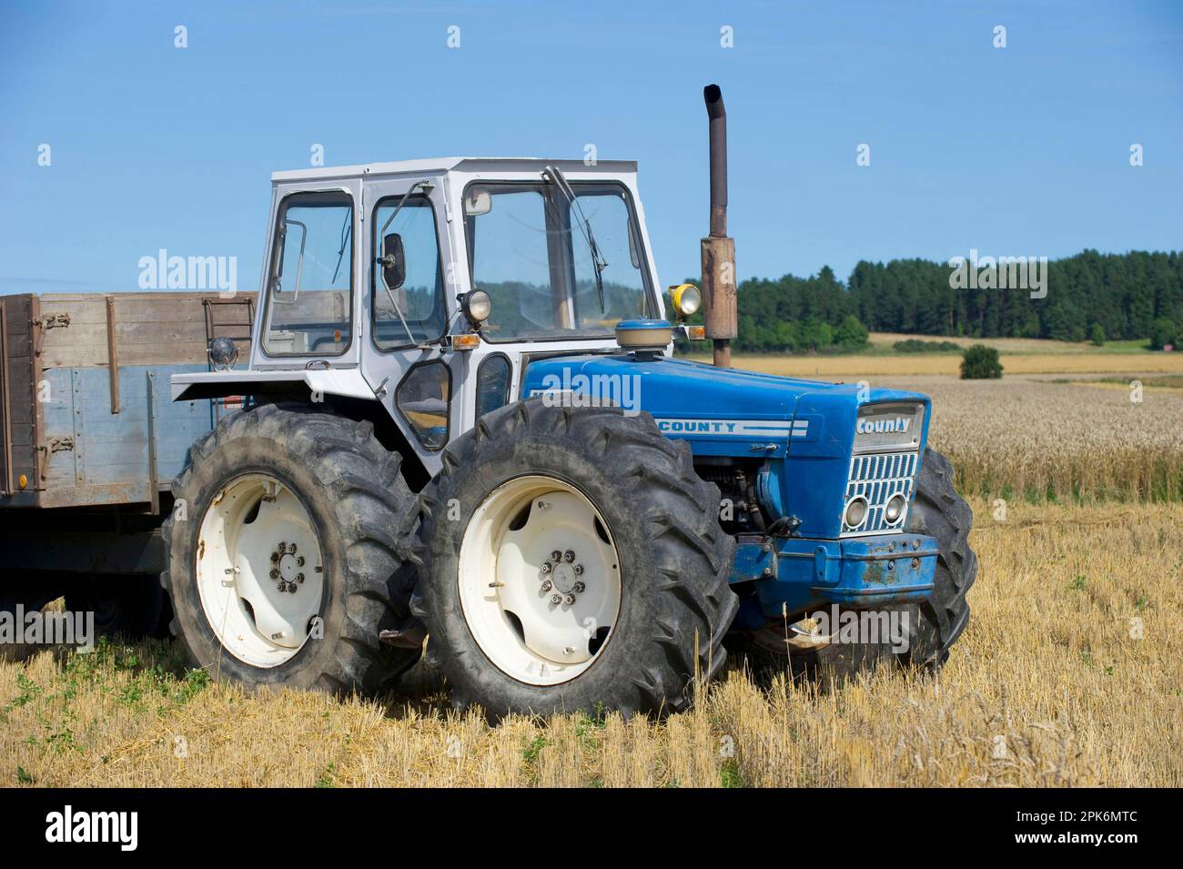 County tractor with trailer, in stubble field at harvest, Sweden Stock ...