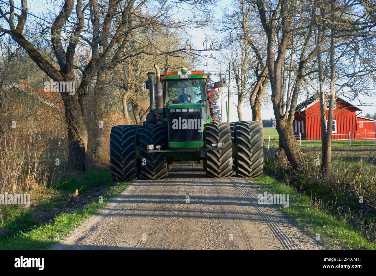 John Deere 9400 tractor with two wheels, driving on small road on the ...