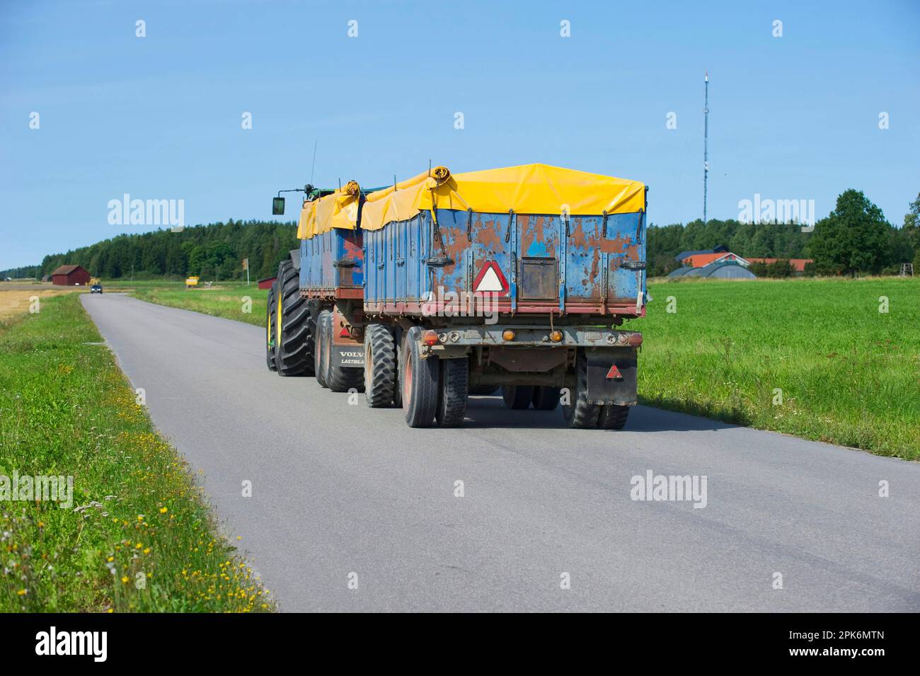 Tractor with covered trailers, transporting harvested grain on country ...