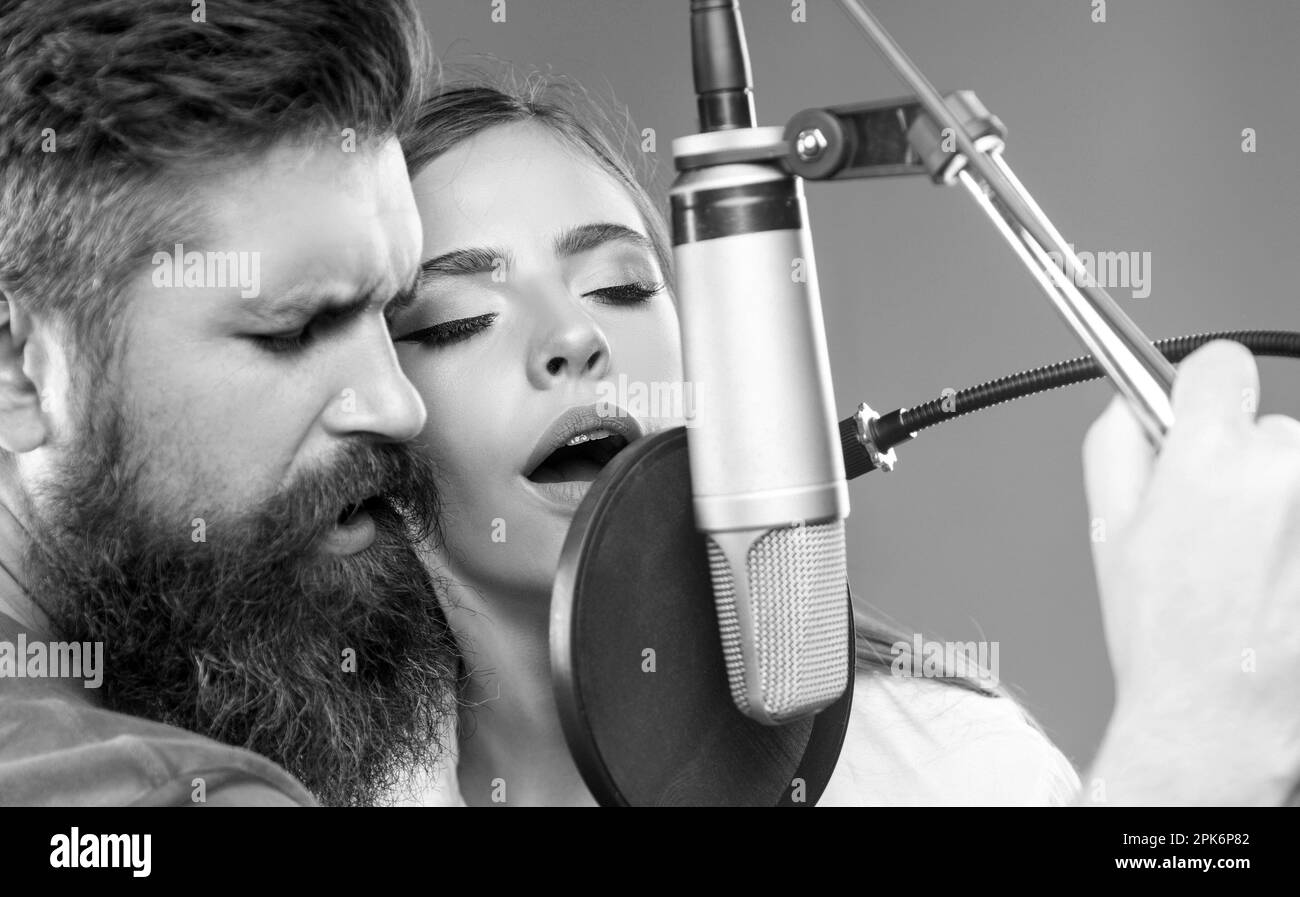 Singer couple is performing a song with a microphone while recording in ...