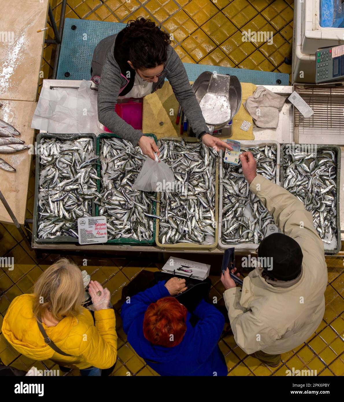 Birds eye colour photo of a stall full of sardines with the seller and ...