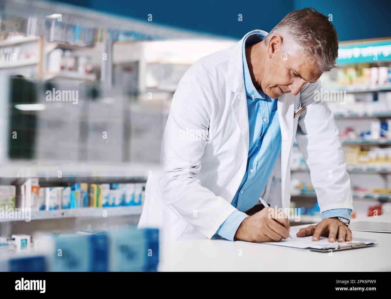 Checking a big prescription. a male pharmacist writing on a clipboard ...