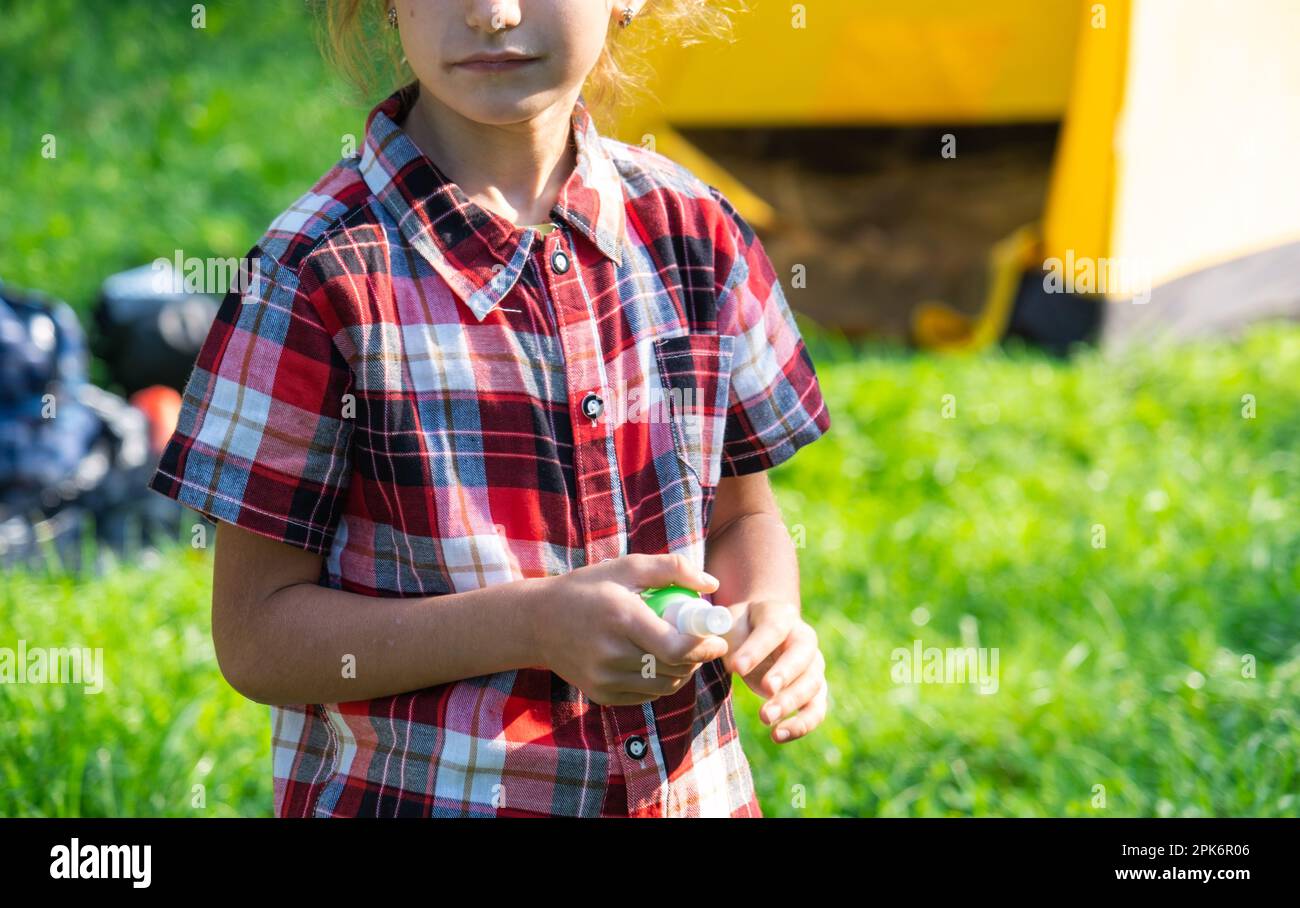 Girl sprays mosquito spray on the skin in nature that bite her hands ...