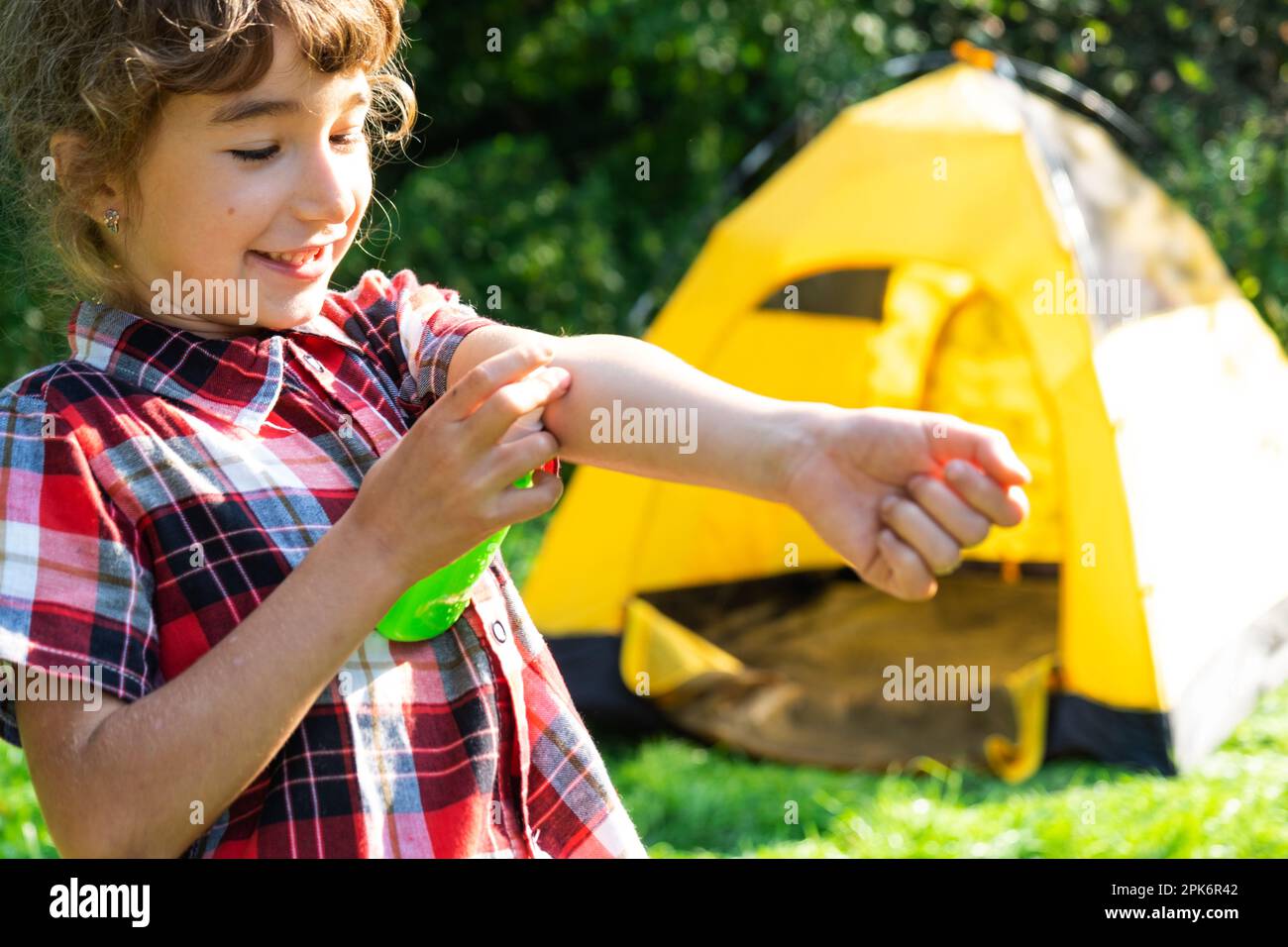 Girl sprays mosquito spray on the skin in nature that bite her hands ...