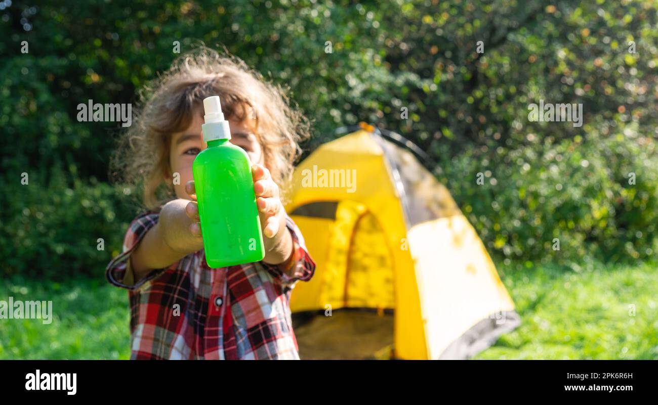 Girl sprays mosquito spray on the skin in nature that bite her hands ...
