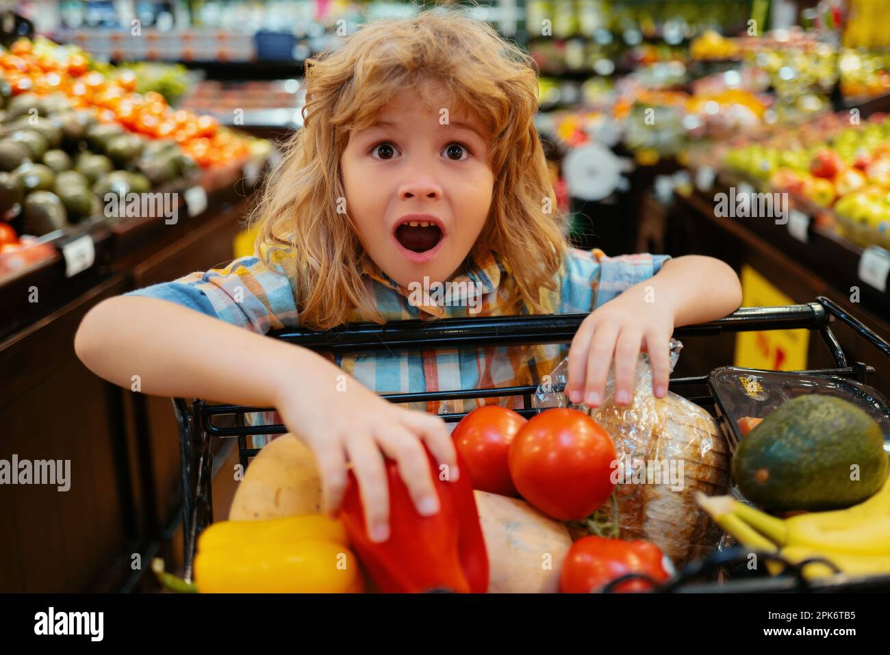 Child in the supermarket. Funny excited little boy wit shopping cart ...