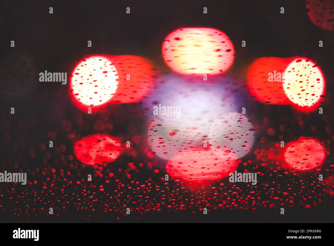Shiny bright red bokeh lights glowing behind wet glass window with ...