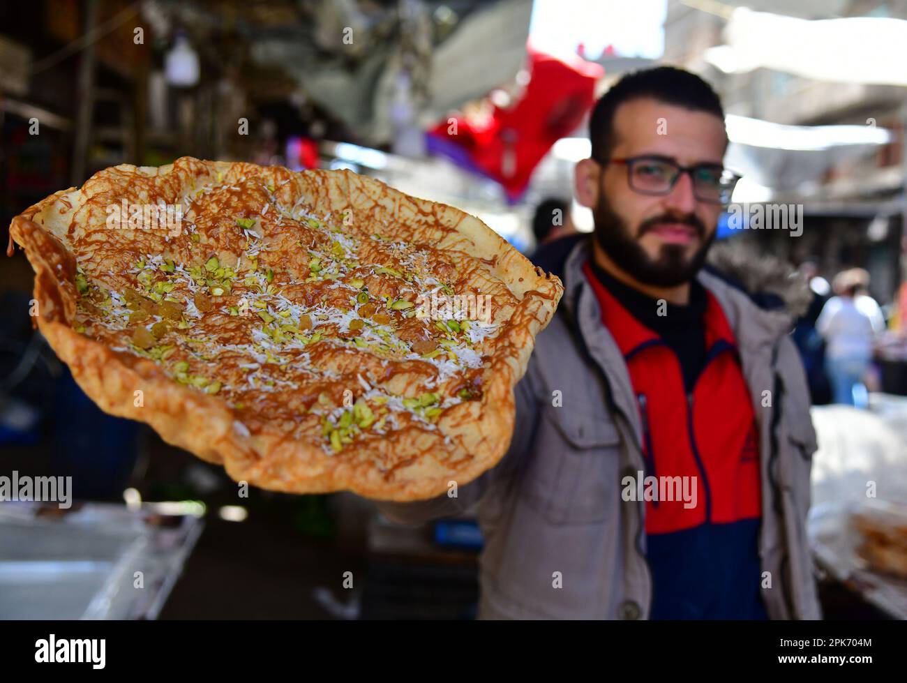 Damascus, Syria. 5th Apr, 2023. A street vendor displays a Naem cake, a ...