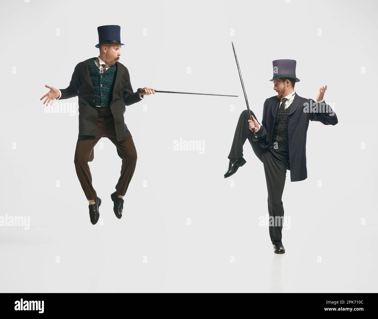 Portrait of two men, friends wearing classic suits jumping and fighting ...
