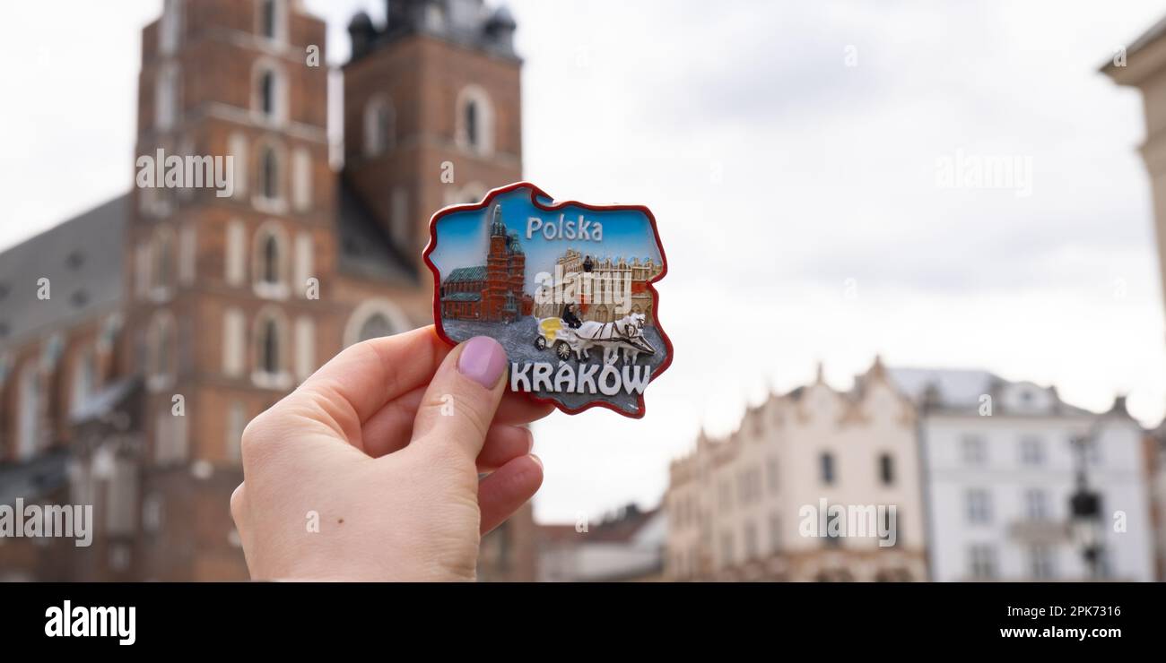 Female hand holding souvenir magnet next to St. Mary's Basilica on the ...
