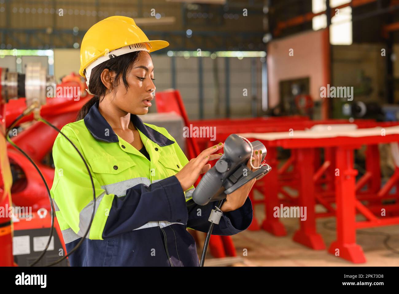 Professional female mechanical engineer in yellow hard hat and safety ...