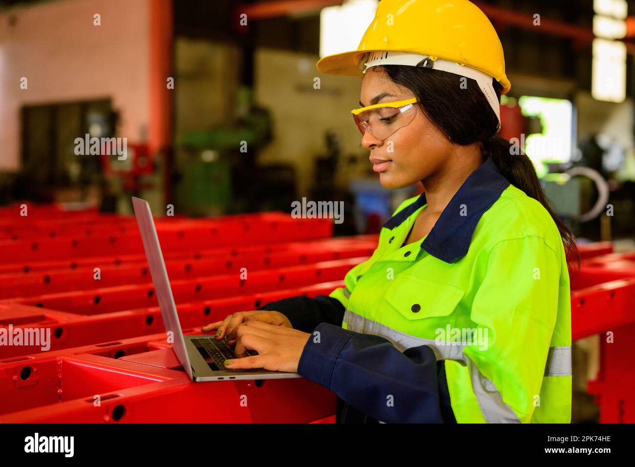 Portrait of female mechanical engineer in yellow hard hat and safety ...