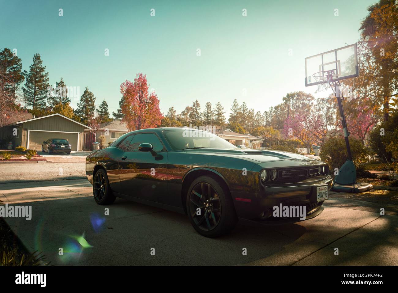 A black Dodge vehicle parked in front of a basketball hoop in an ...