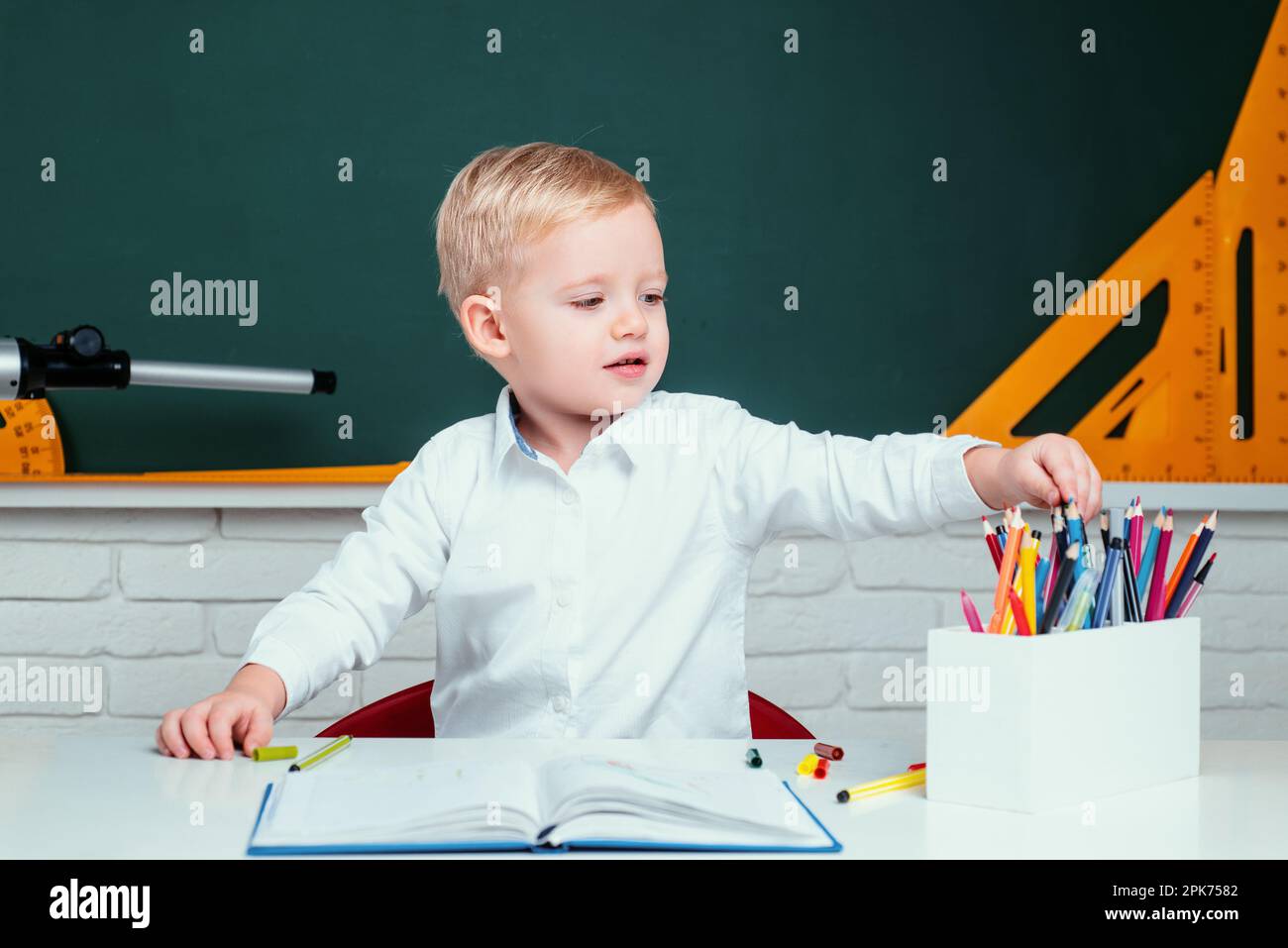 Kid gets ready for school. Schoolkid or preschooler learn. Cute child boy in classroom near ...
