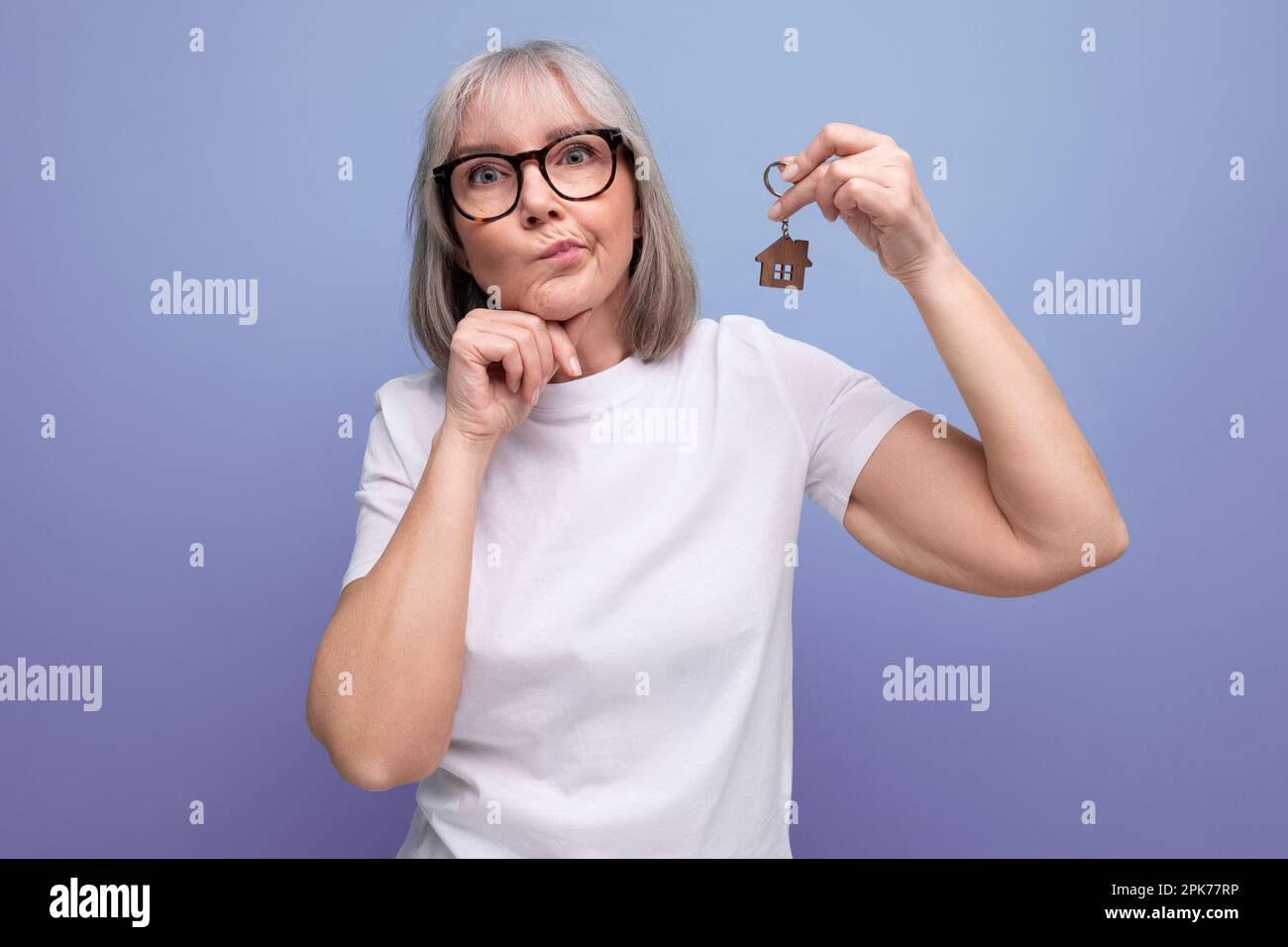 social insurance. mature woman holding secure keys on studio background ...