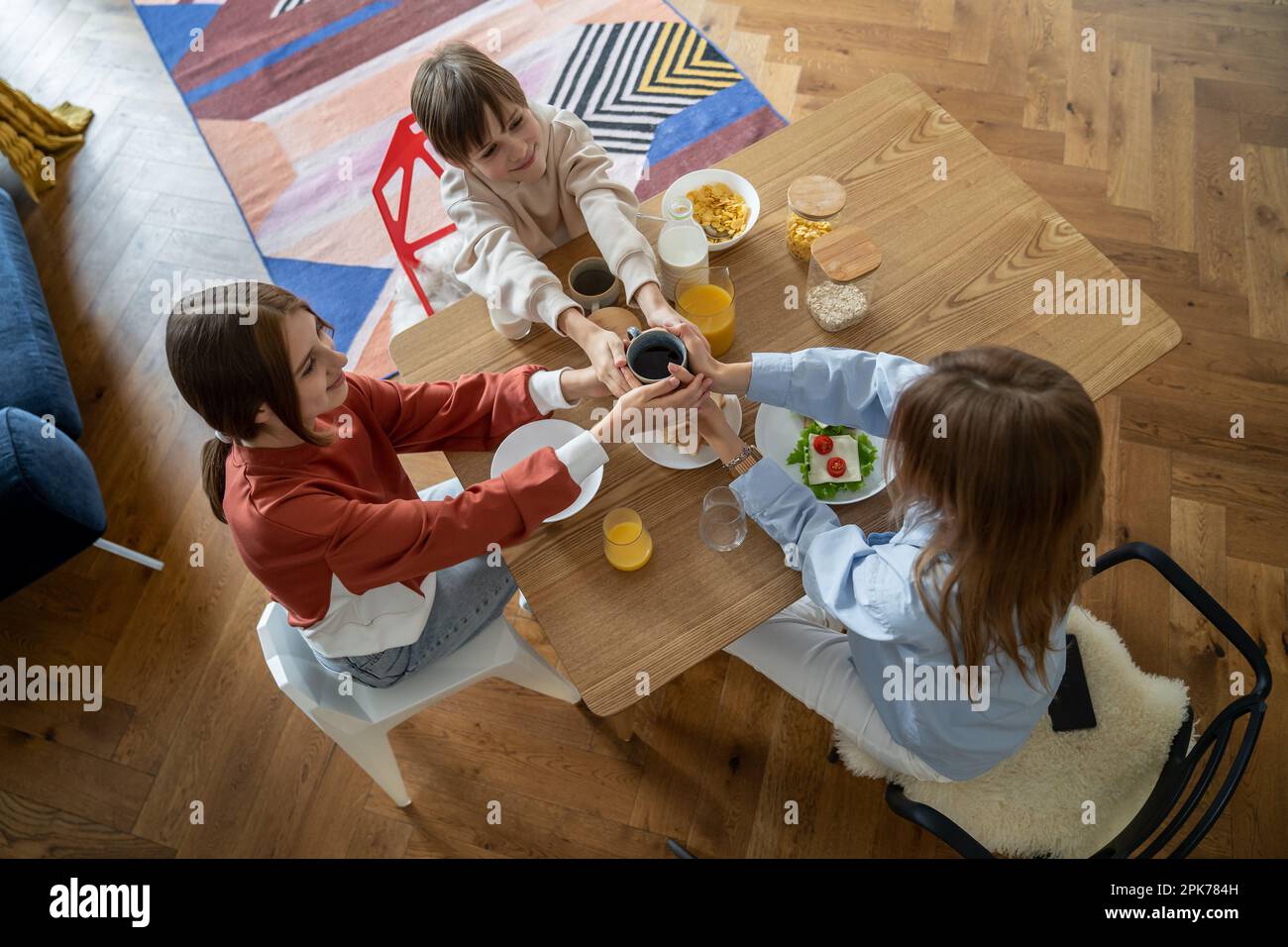 Happy family of three mother and two kids holding one cup of tea while ...