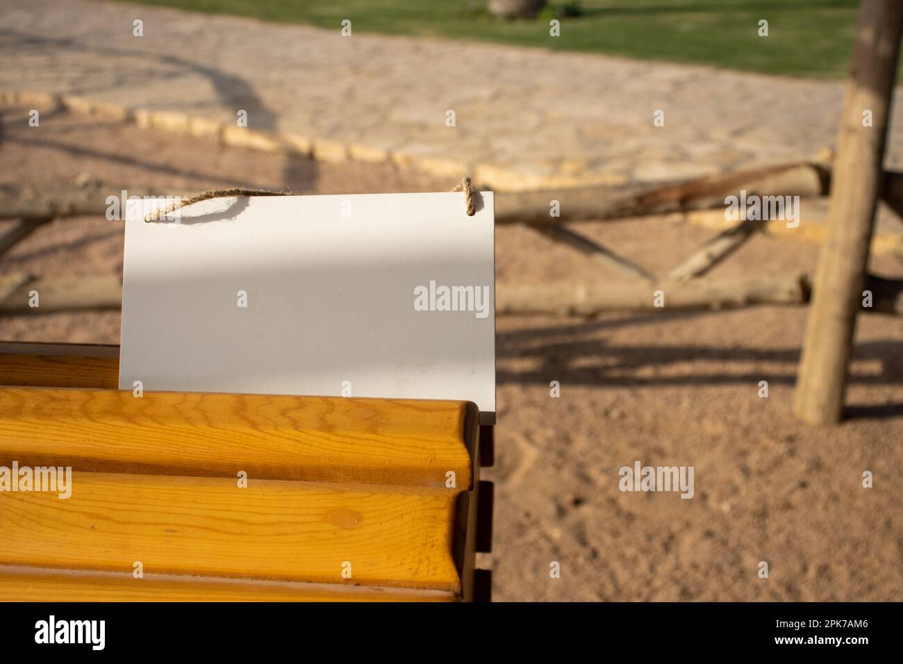 on a park bench white hanging picture sign with empty free space for ...