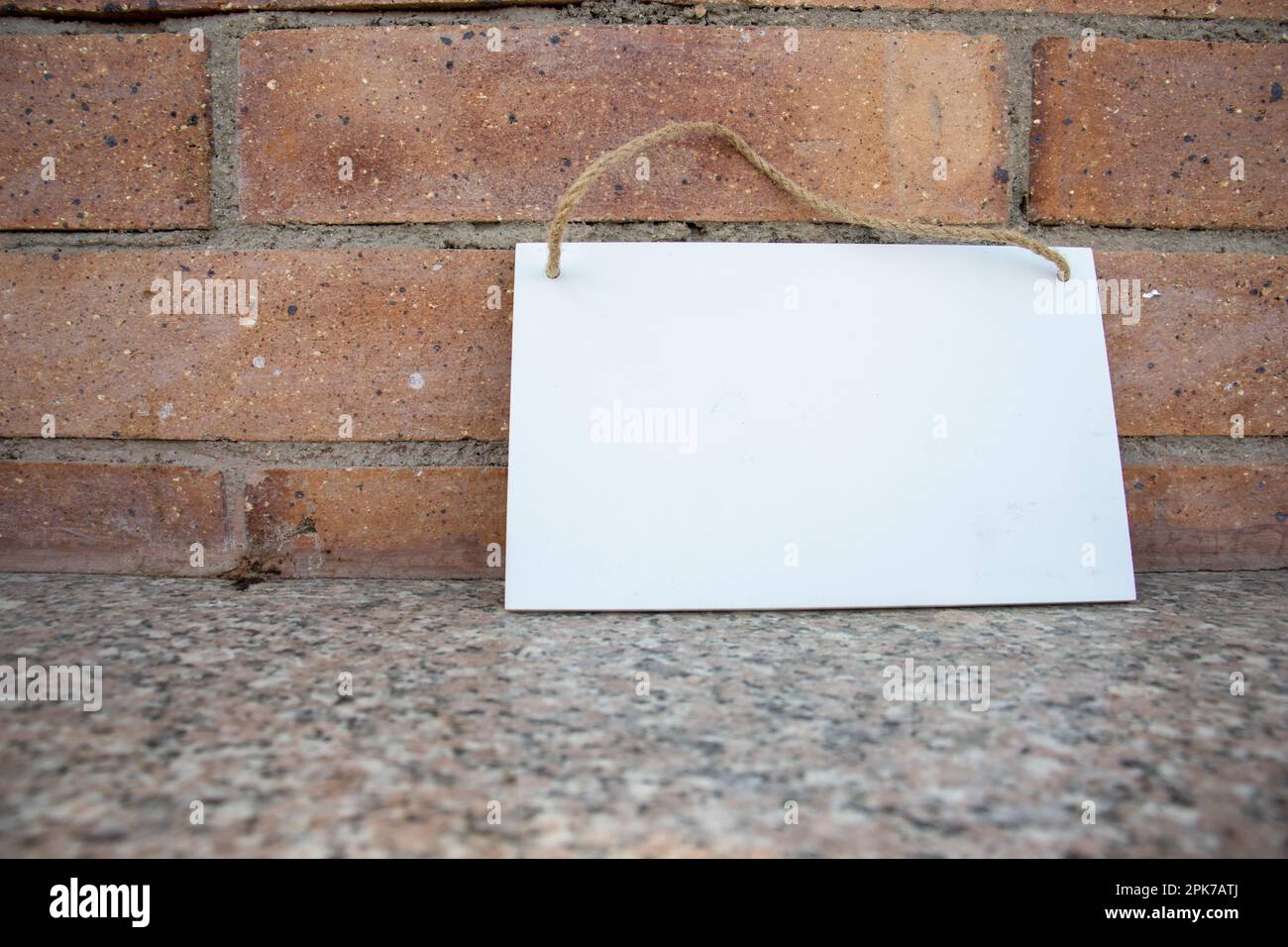 orange brick background with white hanging picture sign with empty free ...