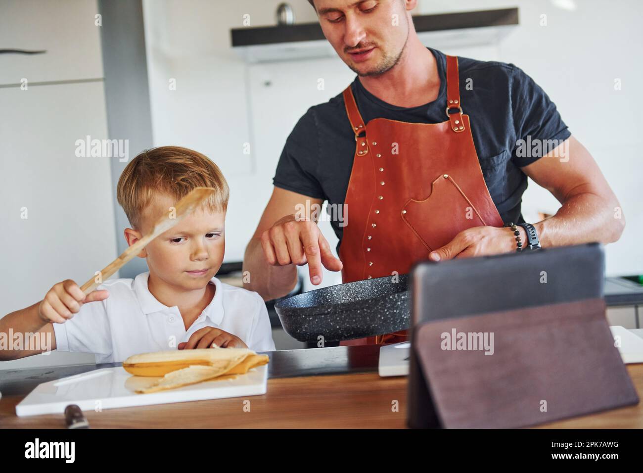 Learning how to cook. Father and son is indoors at home together Stock ...