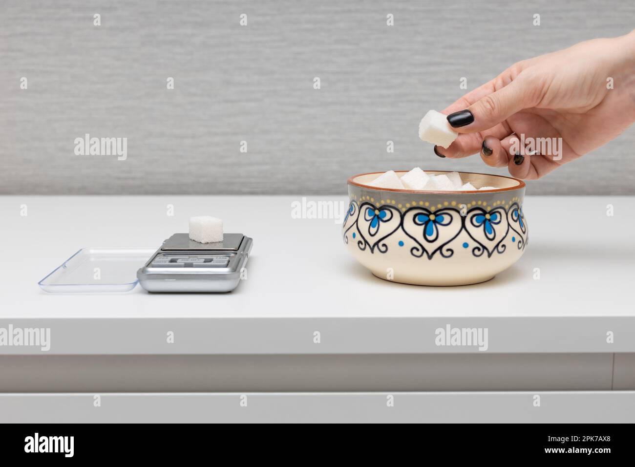 woman weighing a cube of sugar on a small scale. scales for small items ...
