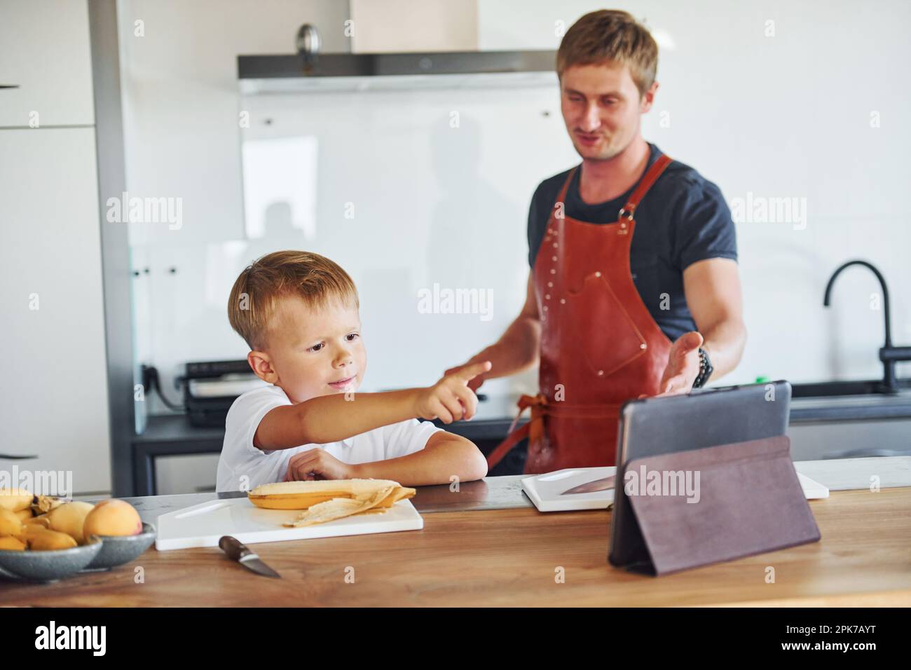 Using tablet to learn how to cook. Father and son is indoors at home ...