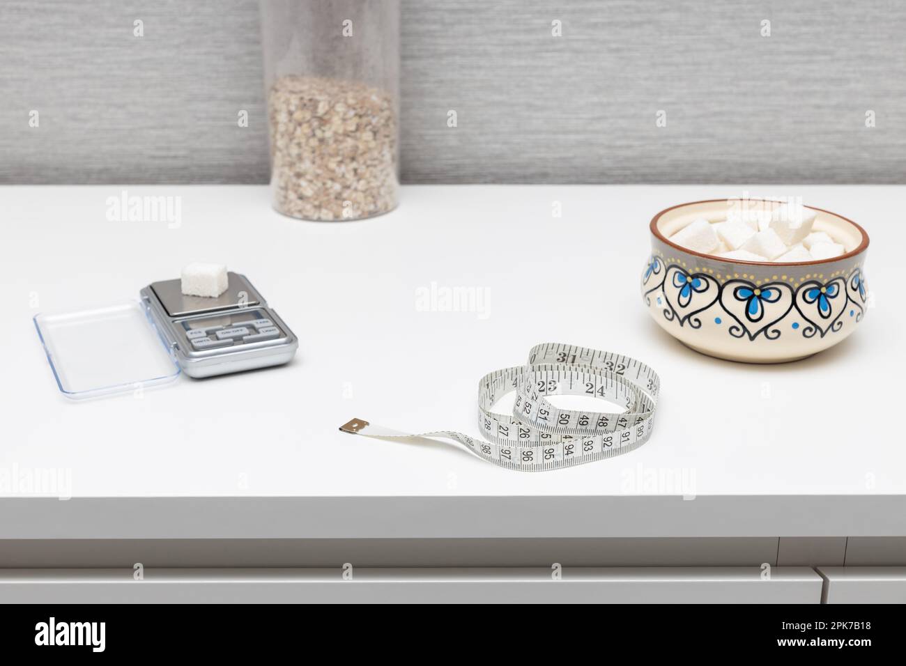 a sugar cube lies on a small scale. white sugar cubes. measuring tape ...