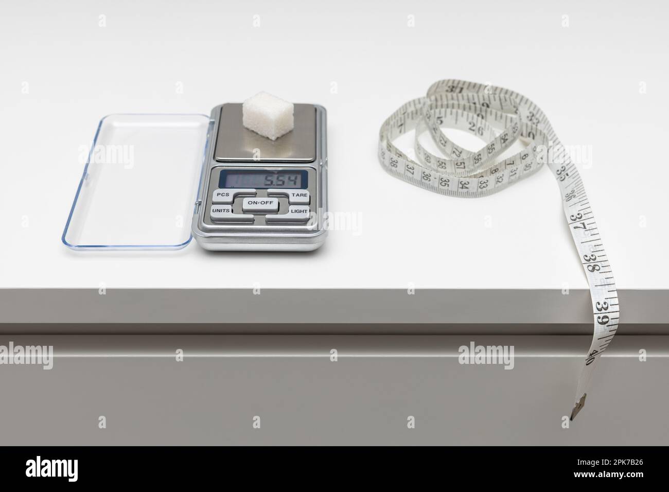 a sugar cube lies on a small scale. white sugar cubes. sugar control. healthy lifestyle. High ...