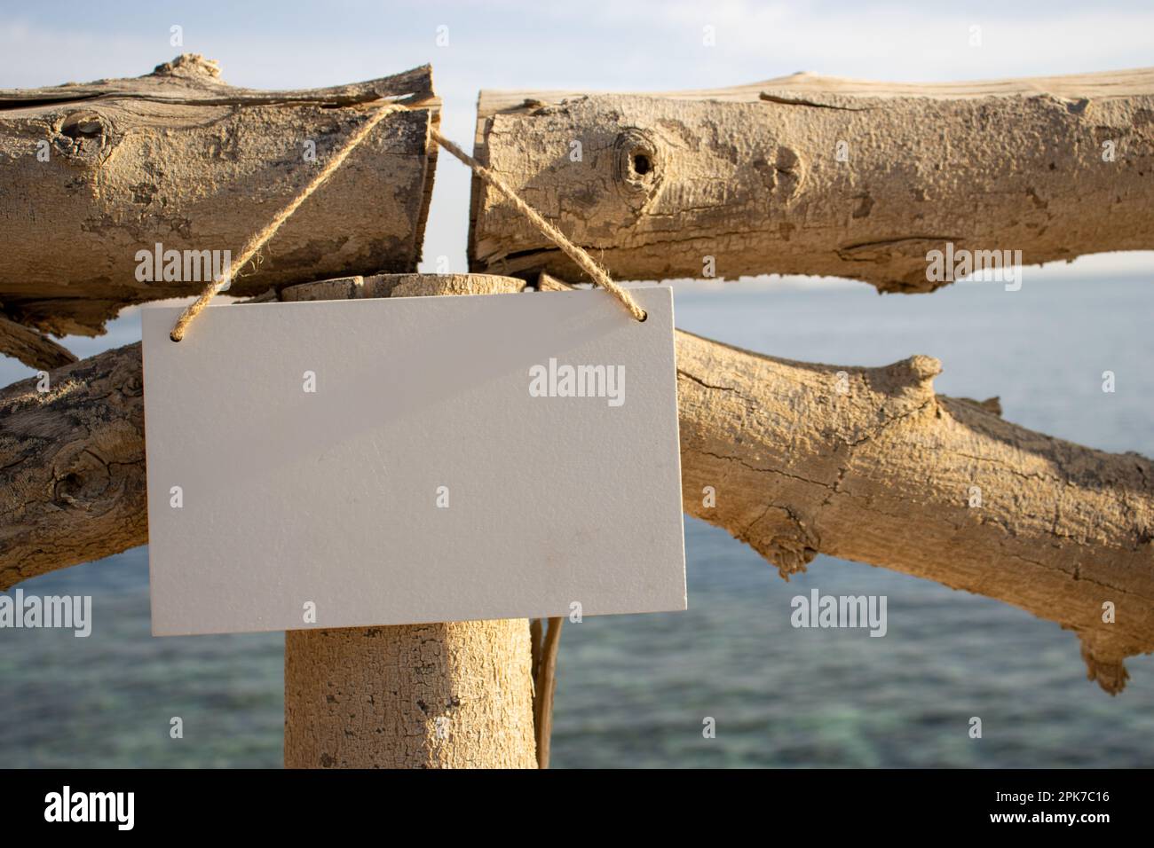 rustic fence with the sea behind and a white hanging picture sign with ...