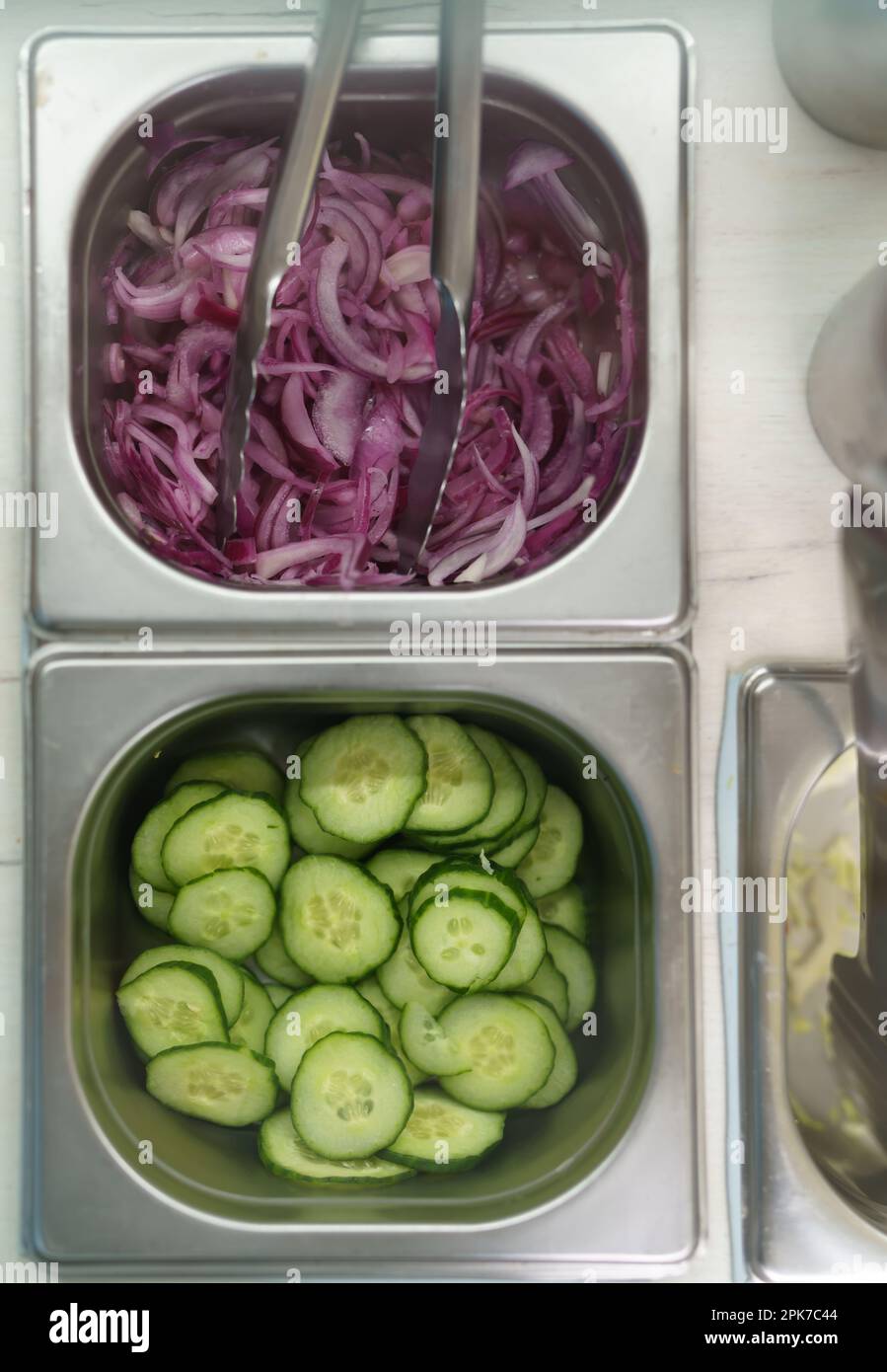 Sliced fresh cucumbers and red onions in containers, shot directly from ...