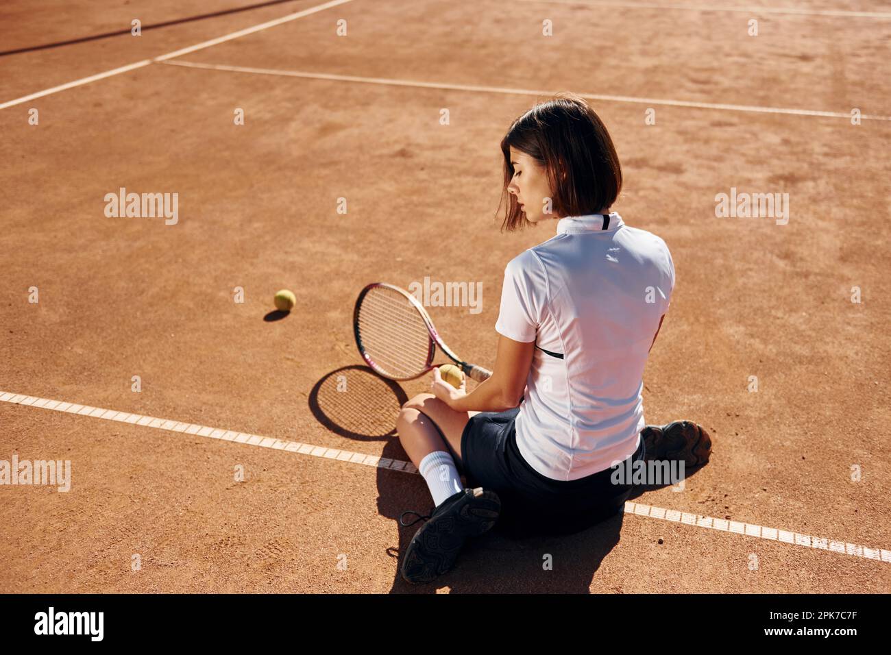 Rear view. Female tennis player is on the court at daytime Stock Photo ...