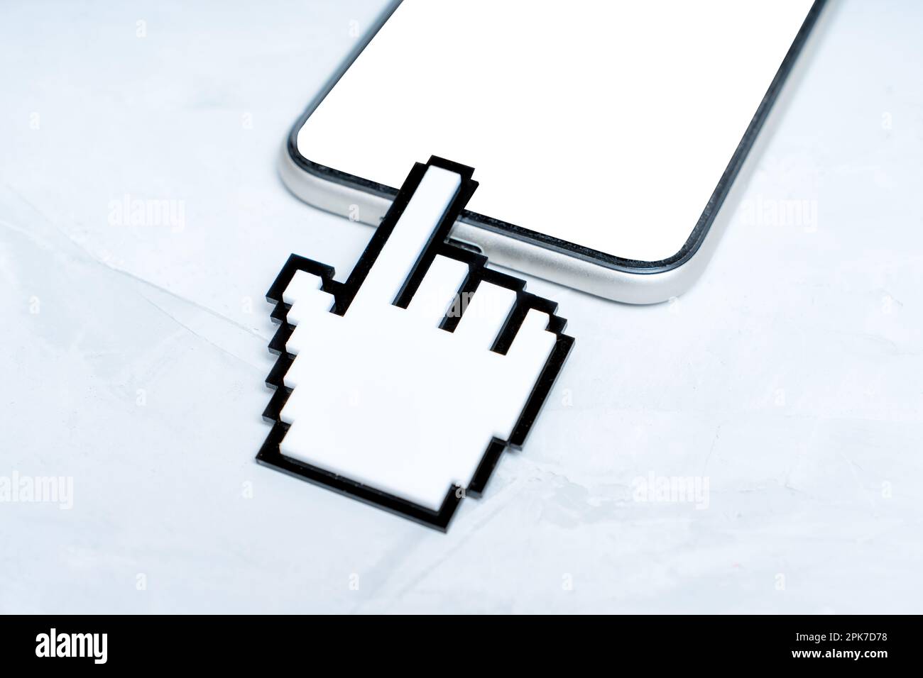 Large plastic pixelated hand cursor model touches a blank screen of a ...